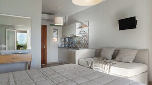 Quarto com uma cama grande, mesa de cabeceira, cômoda, espelho e televisão na parede.