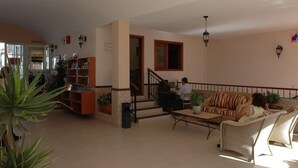 Um hall amplo com escada, área de estar e plantas em vasos.
