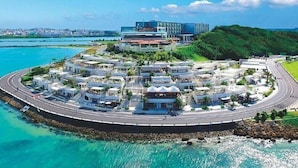 Um resort costeiro com uma estrada circular, moradias na orla marítima e um edifício moderno.