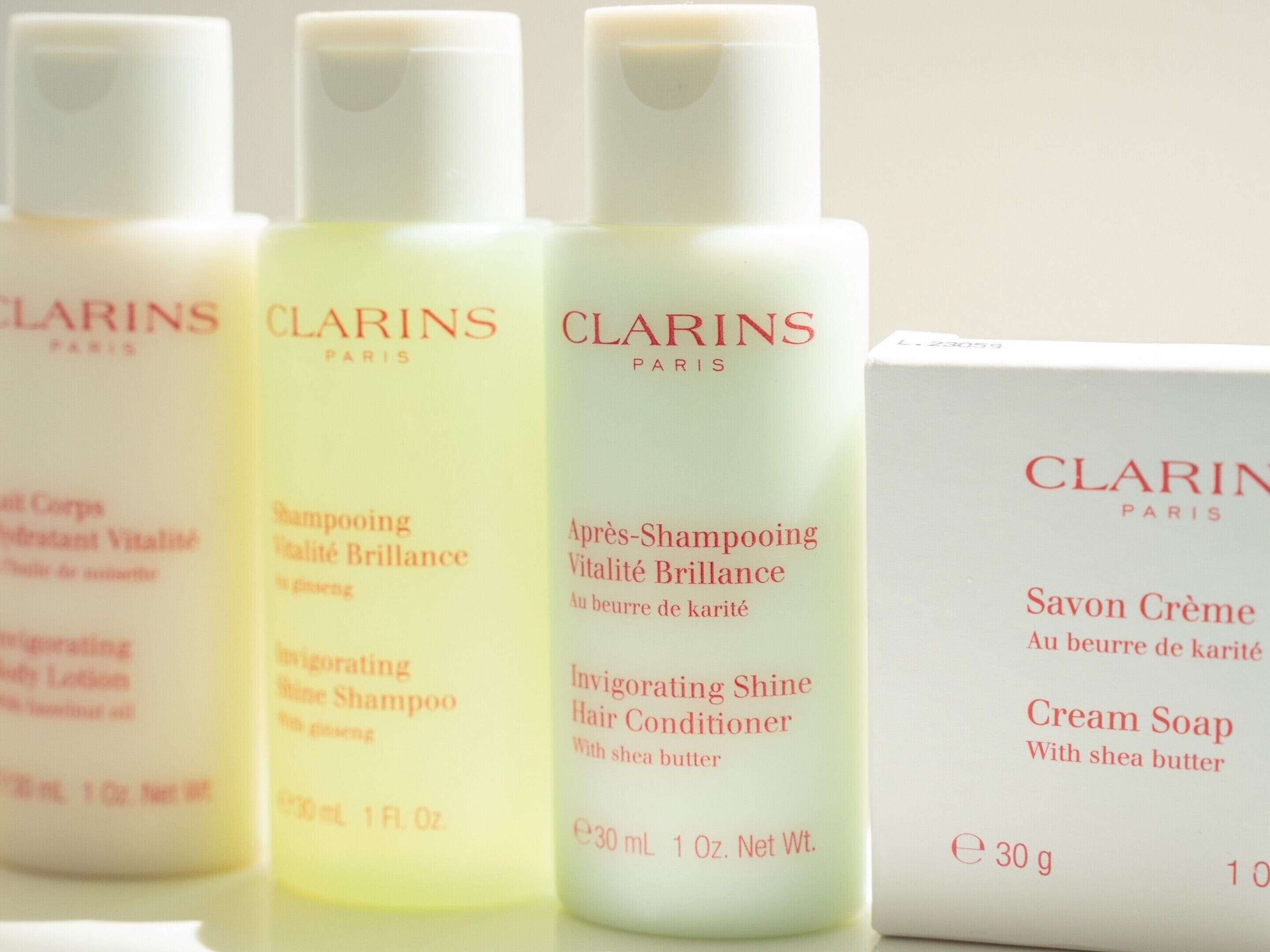 Três frascos de shampoo Clarins Paris e uma caixa de sabonete cremoso Clarins Paris.