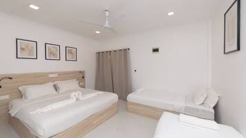 Quarto de hotel com duas camas, um ventilador de teto e três quadros na parede.