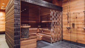 Uma sauna com bancos de madeira e divisória de vidro.