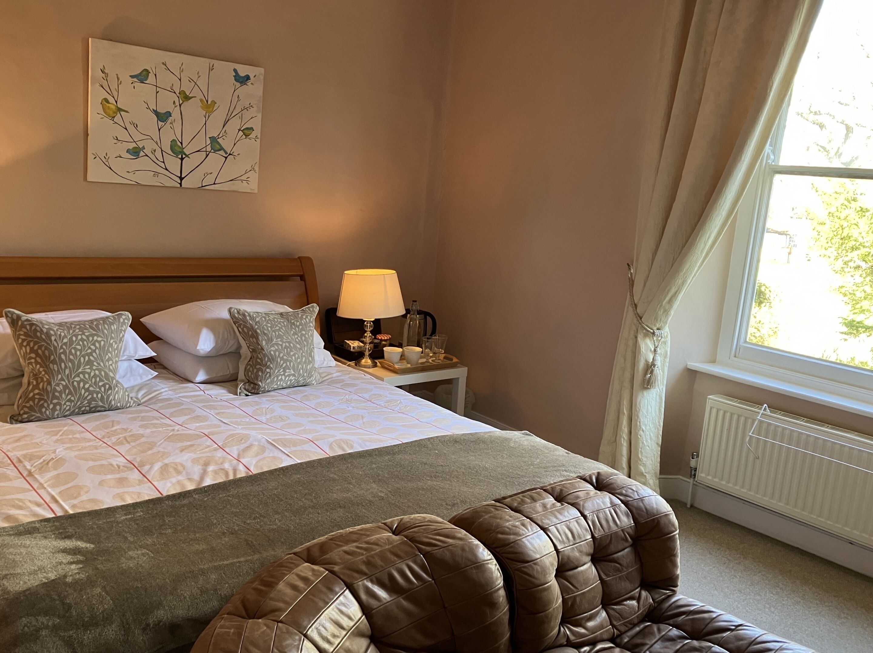 Cama bem arrumada com roupa de cama estampada, abajur e um objeto decorativo na parede.