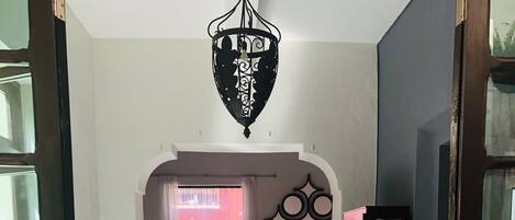 Um quarto espaçoso com uma mesa de vidro, um vaso decorativo com flores e um lustre preto.