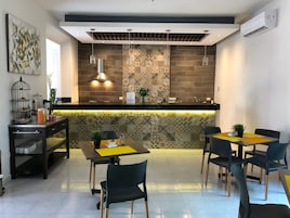 Um restaurante moderno com balcão, cadeiras e uma parede decorativa.