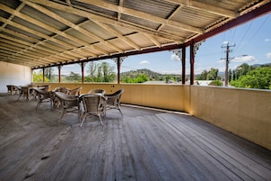 Um espaço ao ar livre coberto, com piso de madeira e móveis de vime.