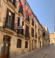 Um edifício com várias varandas, bandeiras e um letreiro indicando 'Sweet Home' e 'Rooms CAMAS'.