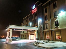Um hotel Comfort Suites com entrada coberta, parede de destaque em pedra e estacionamento.