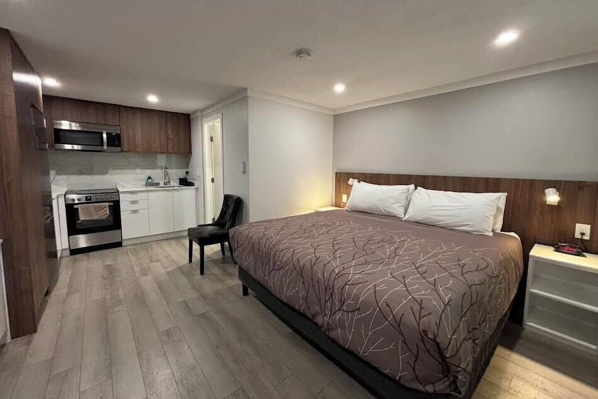 Quarto moderno com cama grande, área de estar separada e cozinha compacta.