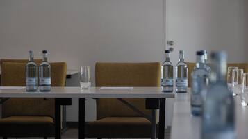 Uma mesa de conferência com garrafas de água e copos, duas cadeiras marrons e uma porta ao fundo.