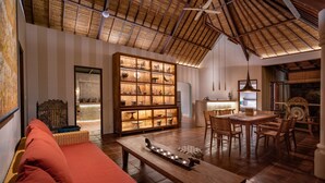 Uma sala de estar espaçosa, com teto alto, mesa de jantar de madeira e aparador embutido.