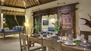 Uma sala de jantar com uma mesa de madeira posta para quatro pessoas, rodeada por painéis de madeira decorados e um espelho grande.