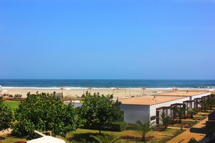 Um resort à beira-mar com vista para o oceano, área de piscina e um jardim com árvores.
