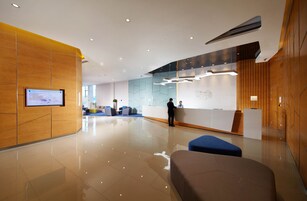 Uma área de recepção moderna com TV de tela plana, balcão de atendimento e um espaço de estar com sofá azul.