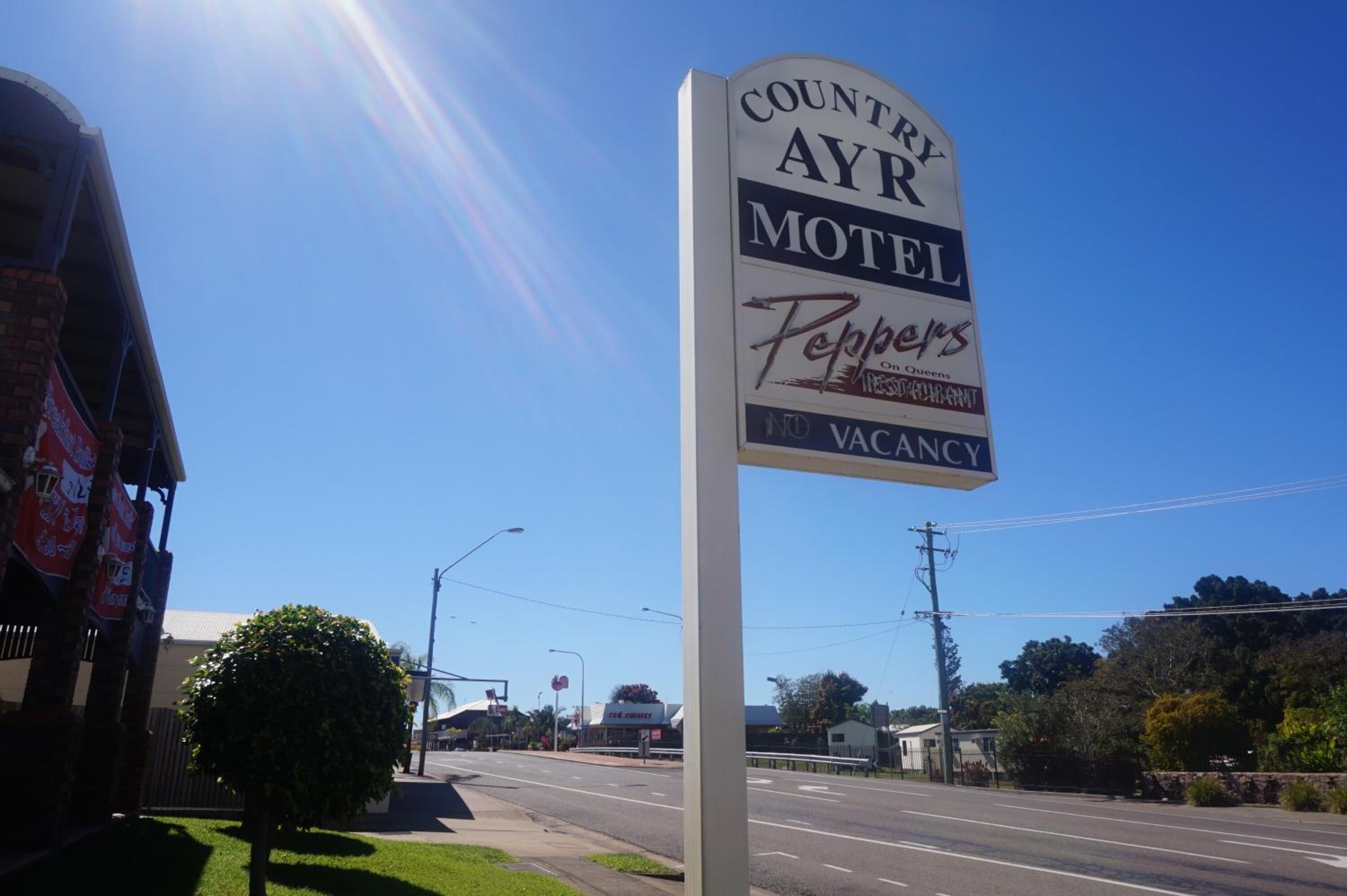 Placa do motel Country Ayr com aviso de quartos disponíveis.