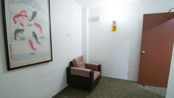 Quarto com uma obra de arte emoldurada de peixes, uma cadeira, uma porta e uma pequena placa com o número 3.