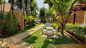 Um jardim com um caminho que leva a uma área de estar com mesas e cadeiras.
