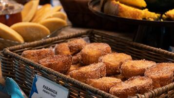 Buffet com diversos alimentos, incluindo pão, doces e uma placa indicando 'RABANADA FRANCE TOAST'.
