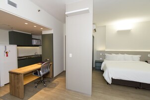 Quarto de hotel compacto com cozinha compacta, uma cama e uma escrivaninha.
