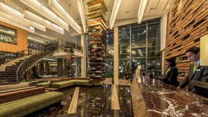 Um hall moderno com piso de mármore, escada e balcão de recepção.
