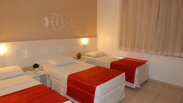Quarto de hotel com duas camas, um enfeite de peixe na parede e uma janela com cortinas.