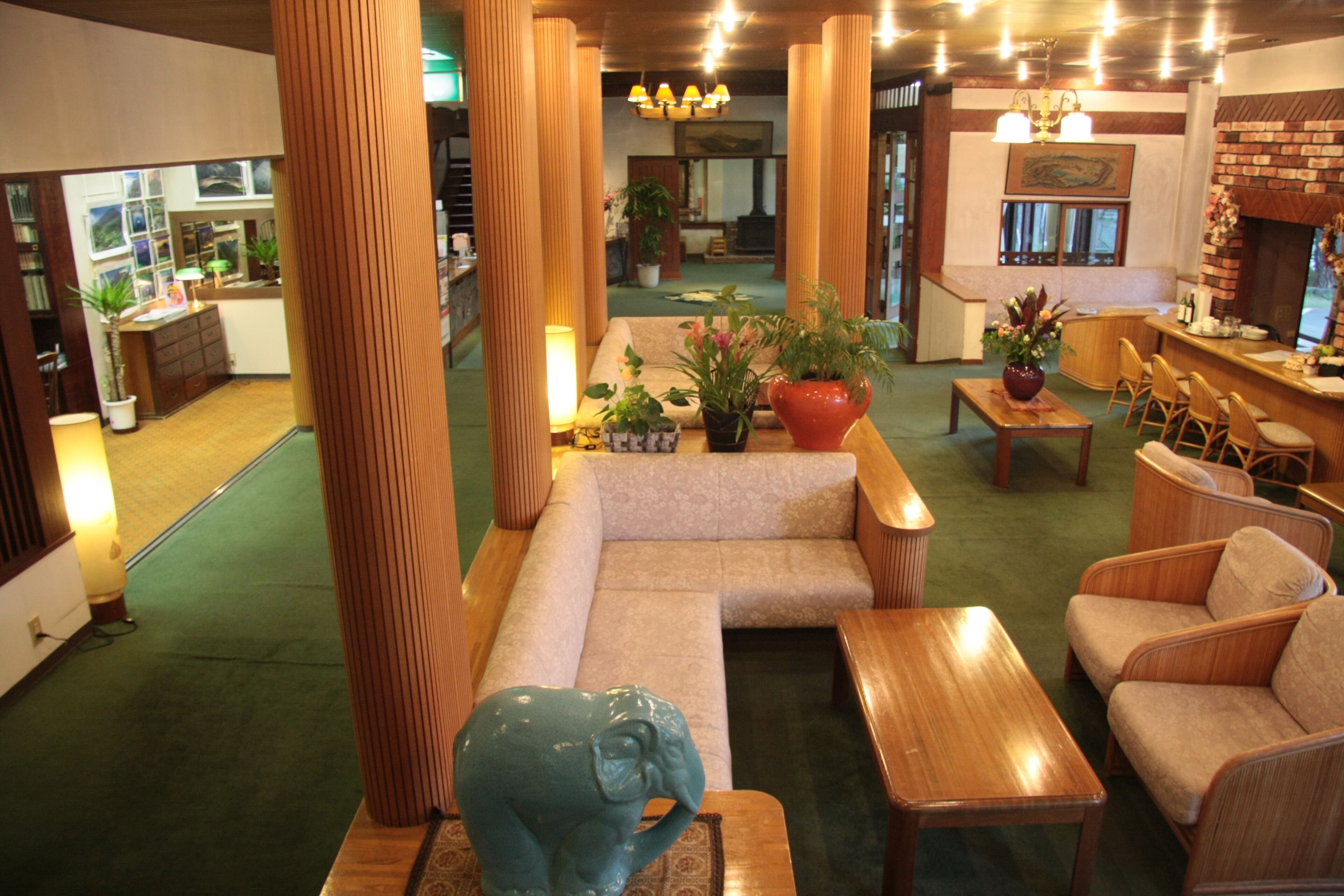 Um hall com sofá, cadeiras, mesa de madeira e uma estátua decorativa de elefante.