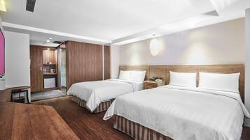 Quarto de hotel com duas camas, uma escrivaninha de madeira, um minibar e um banheiro visível através de uma porta de vidro.