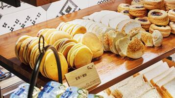Exposição de doces numa pastelaria, com croissants, muffins e pão.