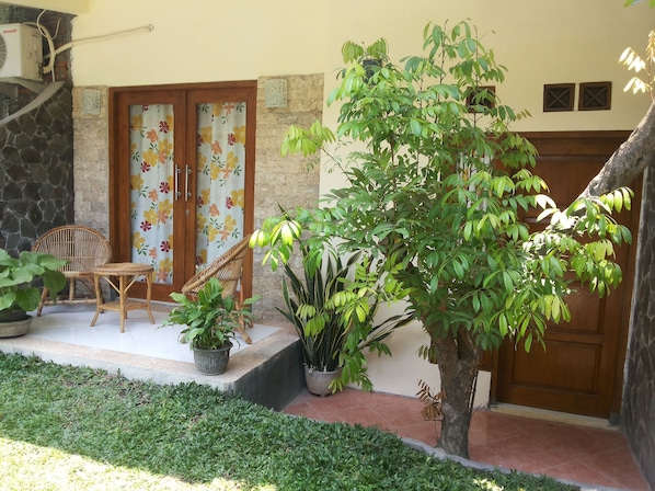 Uma casa com parede de pedra, porta de madeira e planta em vaso no jardim da frente.