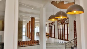 Um hall amplo com escada, grandes colunas de madeira e luminárias pendentes.