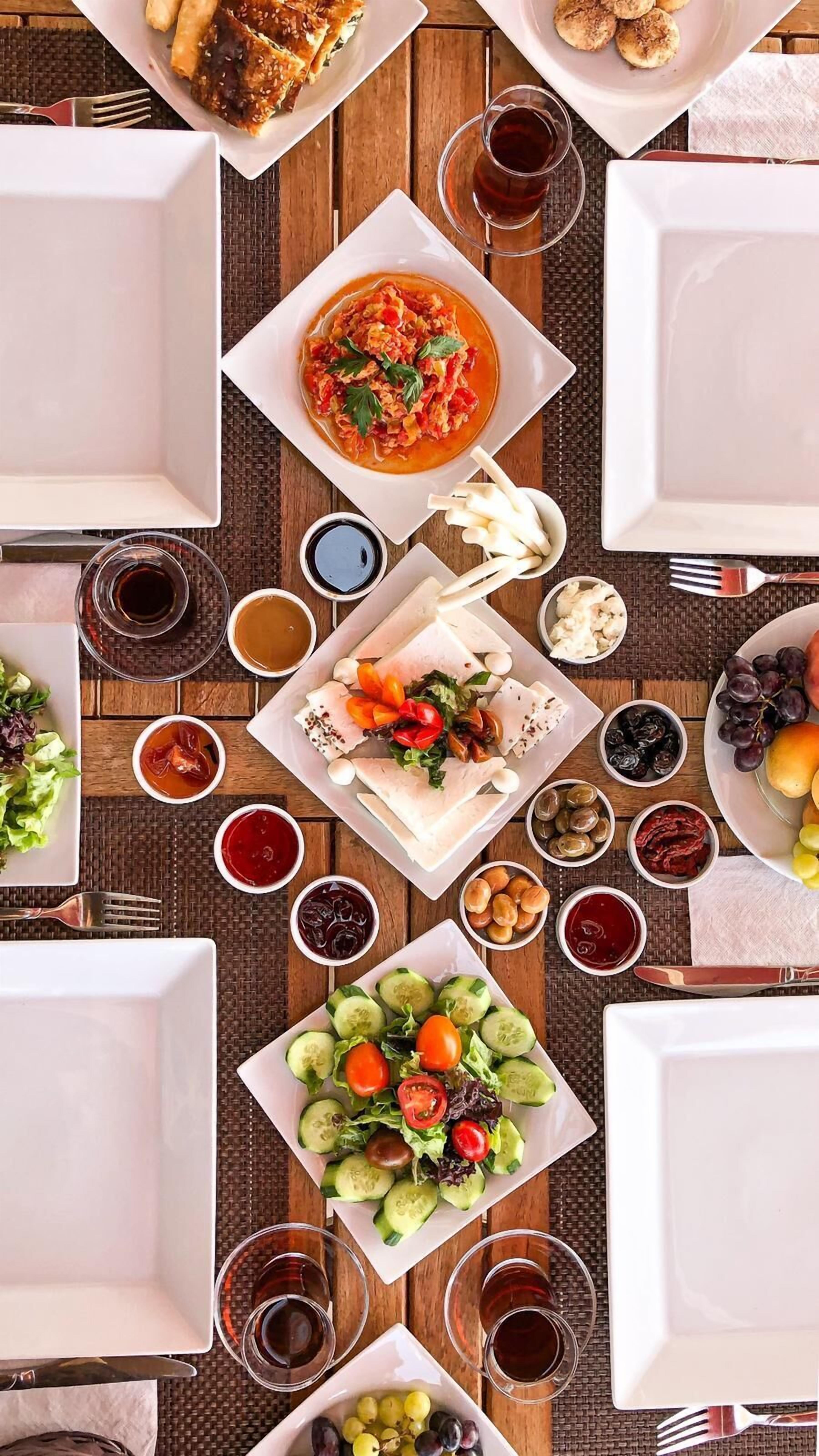 Uma mesa de jantar com diversos pratos, bebidas e acompanhamentos.