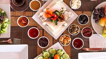 Uma mesa de jantar com diversos pratos, bebidas e acompanhamentos.