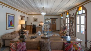 Uma sala de estar ampla com um banco de madeira, uma mesa de centro de vidro e um lustre.