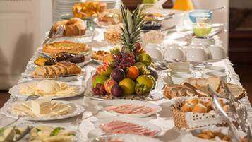 Buffet com diversas opções de comida, incluindo frutas, doces e carnes.