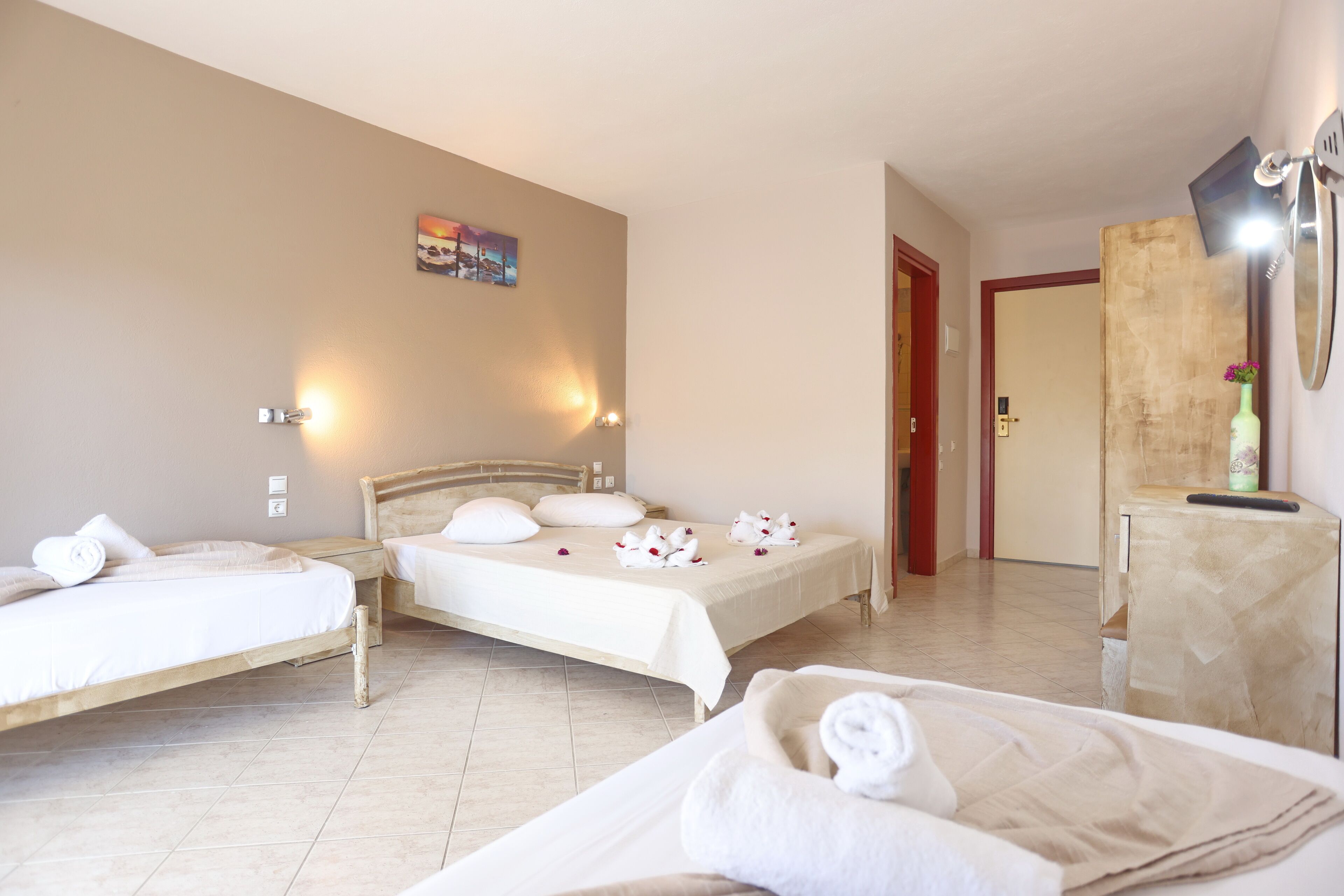 Quarto de hotel com duas camas, um quadro na parede e banheiro com espelho e porta-toalhas.