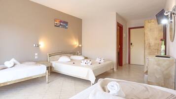 Quarto de hotel com duas camas, um quadro na parede e banheiro com espelho e porta-toalhas.