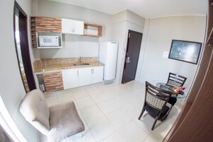 Uma cozinha compacta com micro-ondas, geladeira e um espaço de refeições com cadeira e mesa.