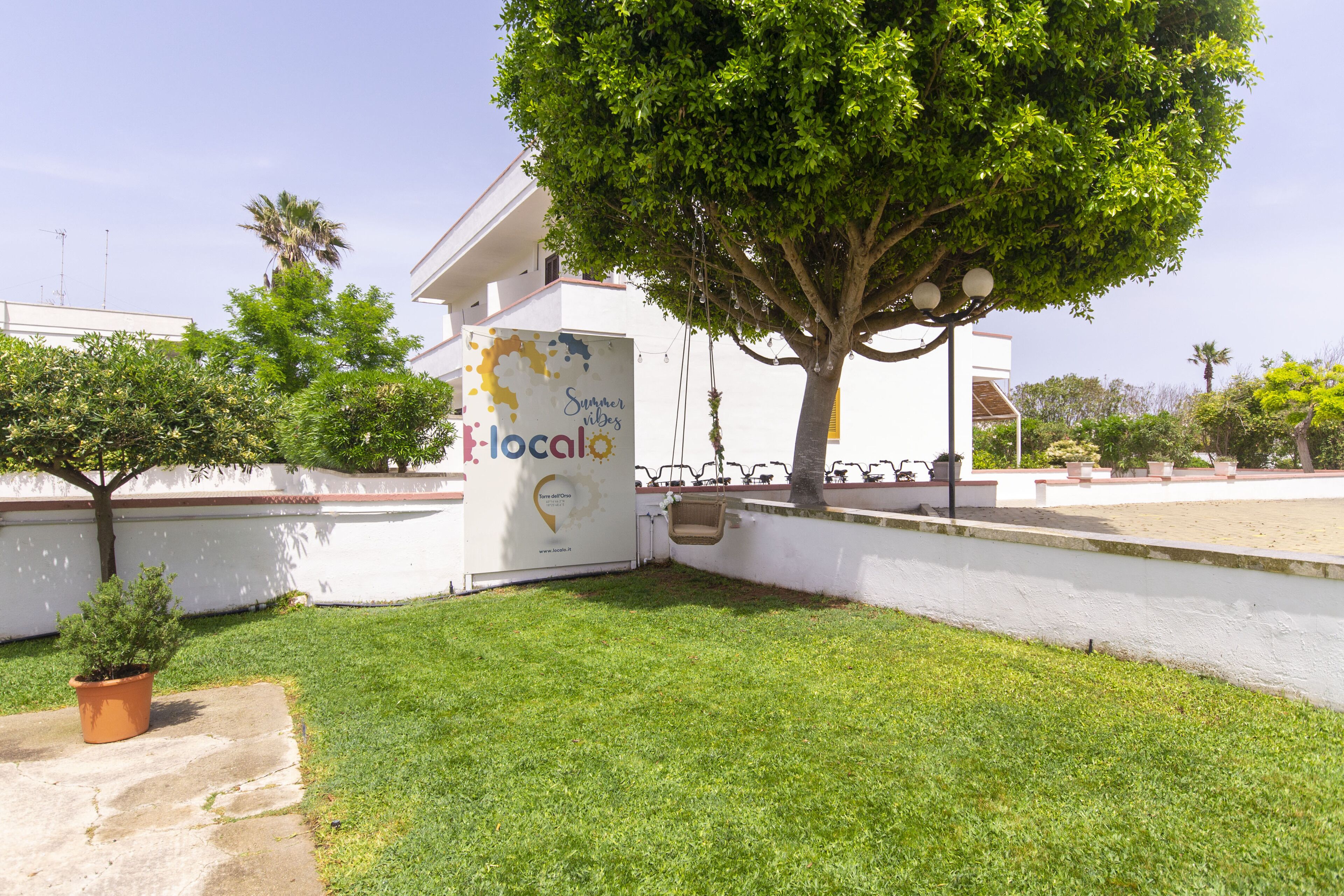 Um edifício com fachada branca, uma árvore na frente e uma placa com o texto "Hacienda".