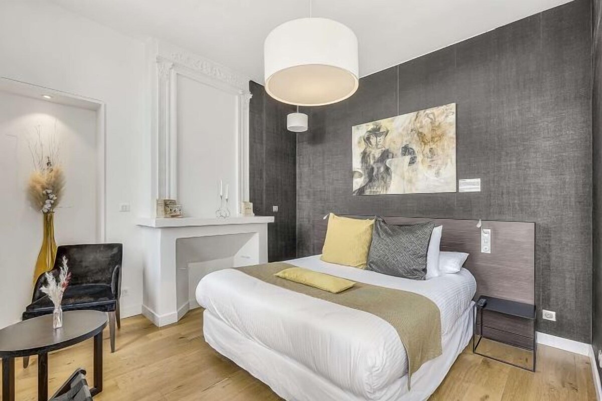 Quarto moderno com uma cama grande, uma mesa de cabeceira, uma cadeira e uma escrivaninha.