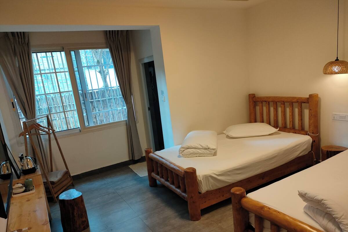 Quarto com cama e cómoda de madeira, espelho e janela com cortinas.