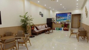 Um saguão de hotel com balcão de recepção, área de estar e uma pintura grande na parede.
