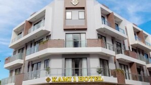 Um hotel com vários andares e uma placa chamativa com a inscrição 'KAMI 1 HOTEL'.