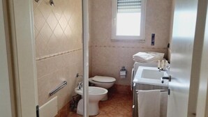 Casa de banho compacta com sanita, bidé e lavatório.