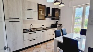 Uma cozinha moderna com armários brancos, puxadores pretos, bancada preta e uma área de jantar com mesa e cadeiras.