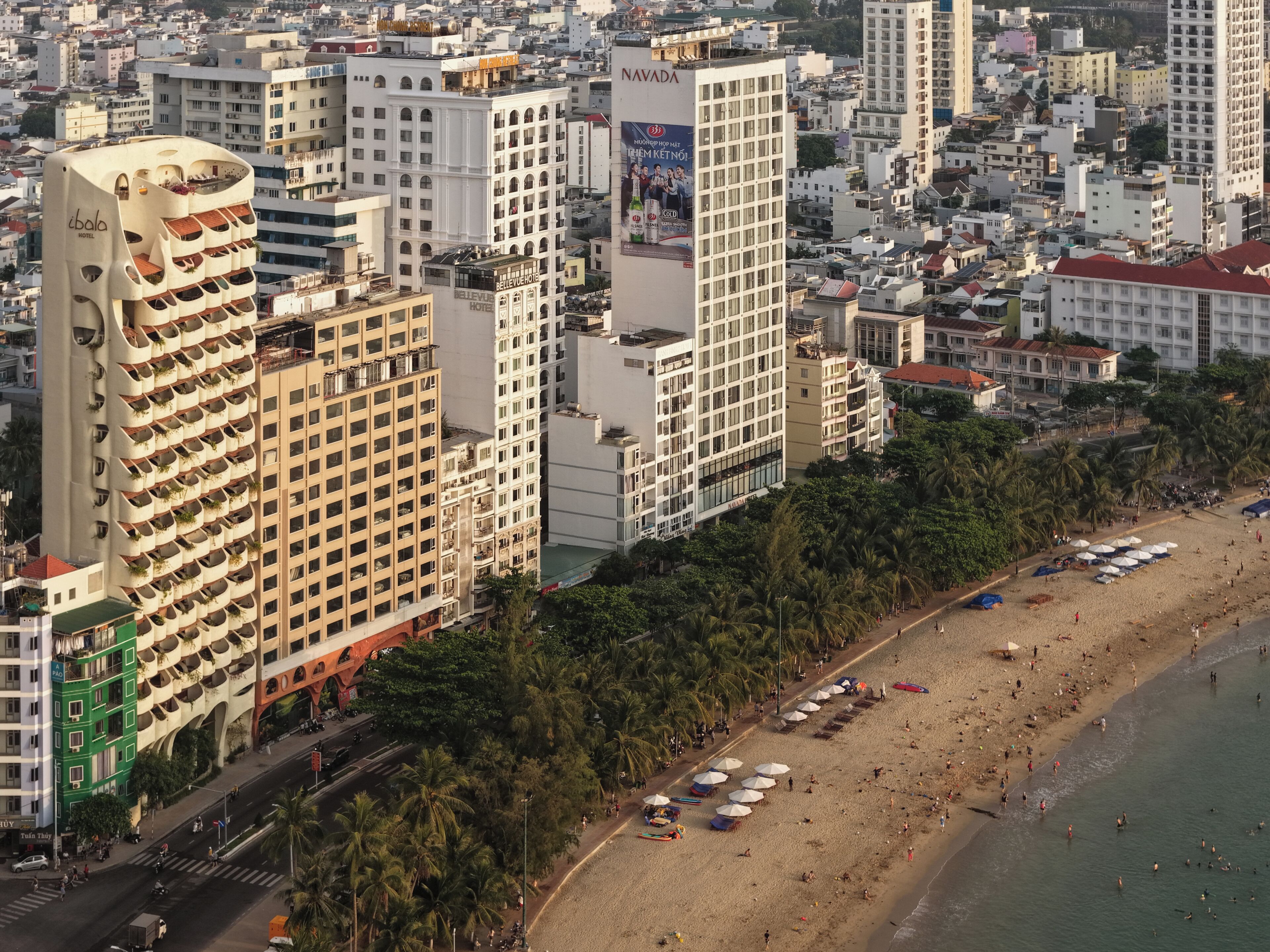 Um hotel moderno alto com várias varandas, localização à beira-mar e vista para o horizonte da cidade.