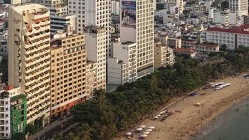 Um hotel moderno alto com várias varandas, localização à beira-mar e vista para o horizonte da cidade.