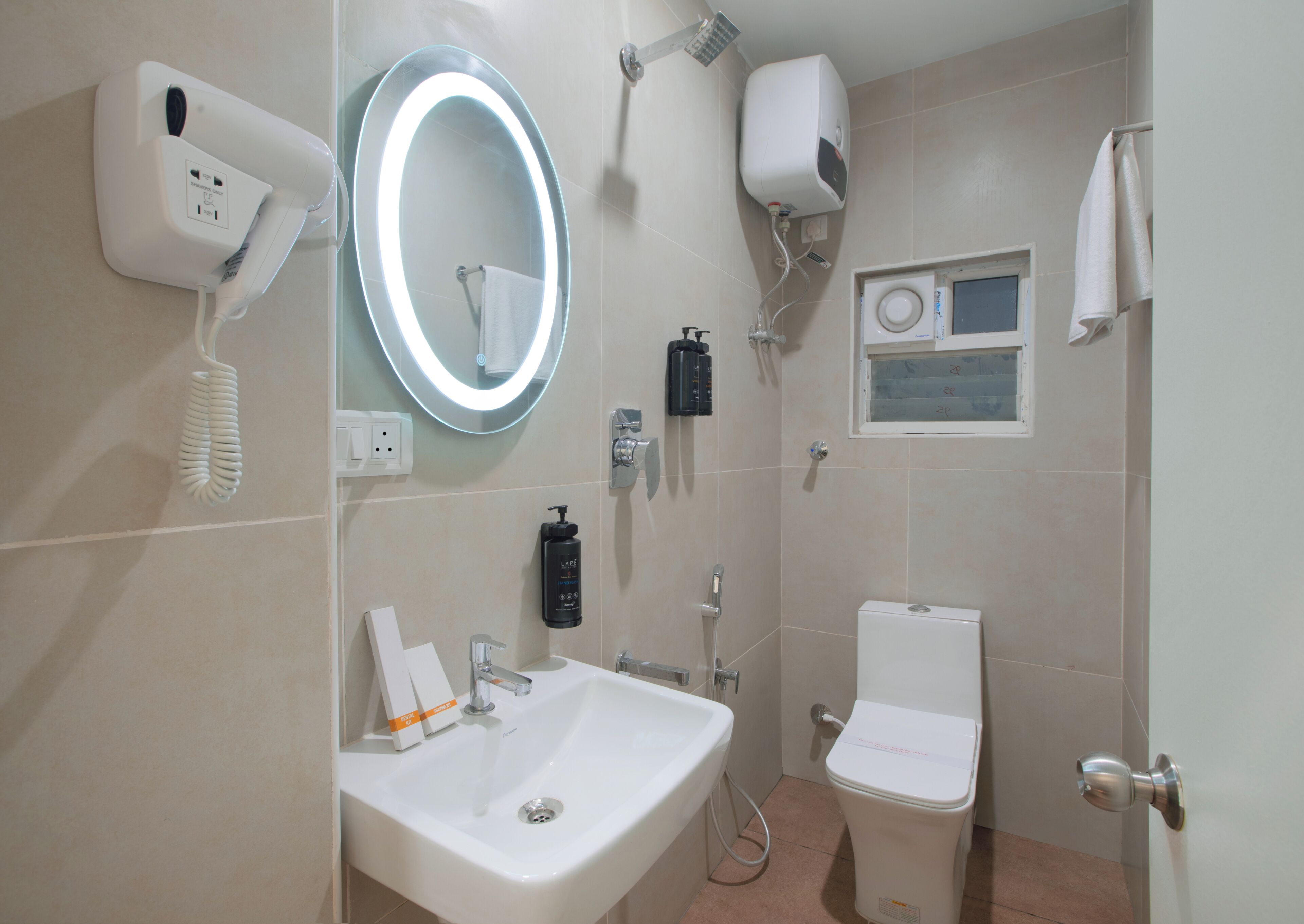Casa de banho com lavatório, sanita, espelho, secador de cabelo e porta-toalhas.