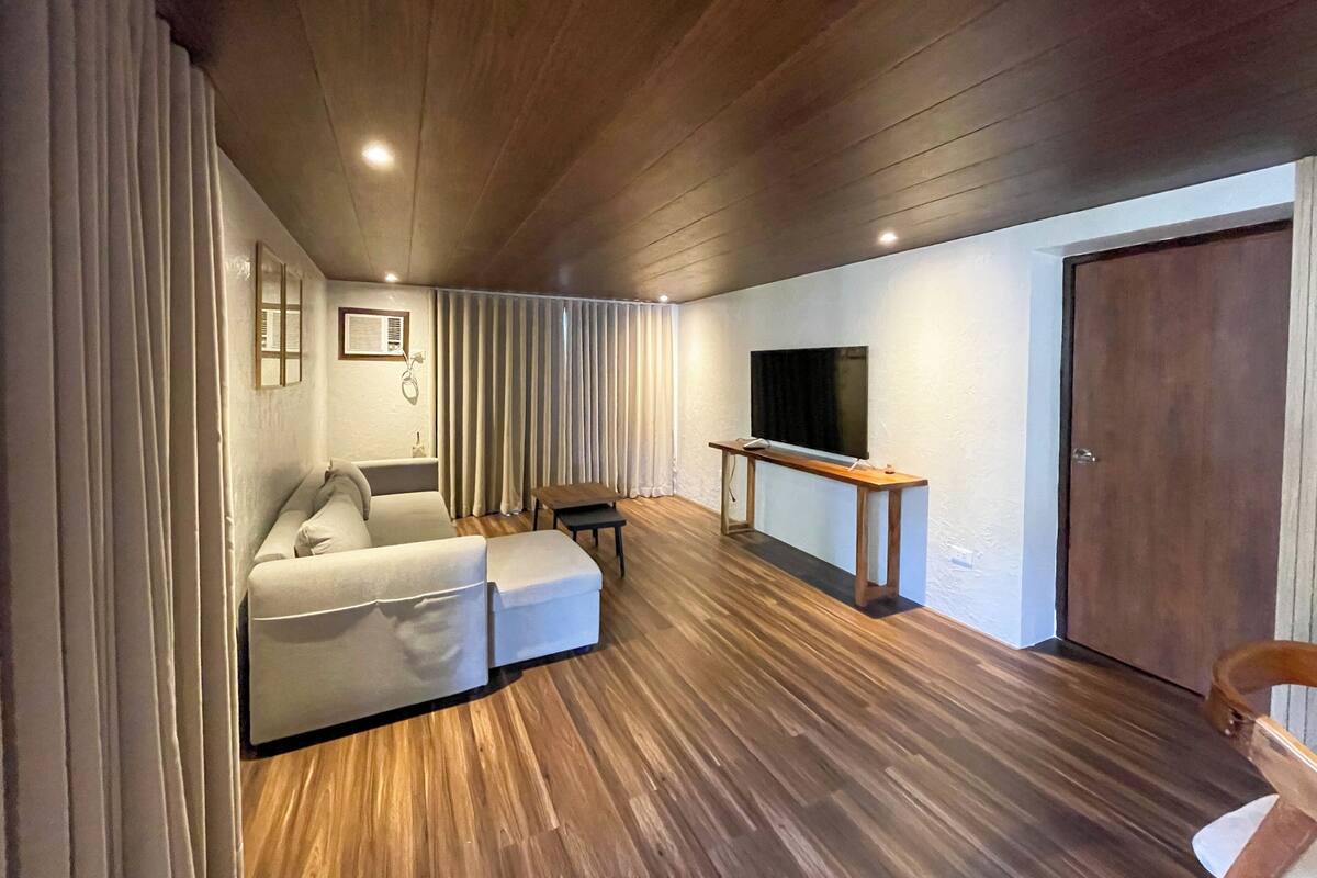 Uma sala de estar moderna com sofá, televisão e piso de madeira.