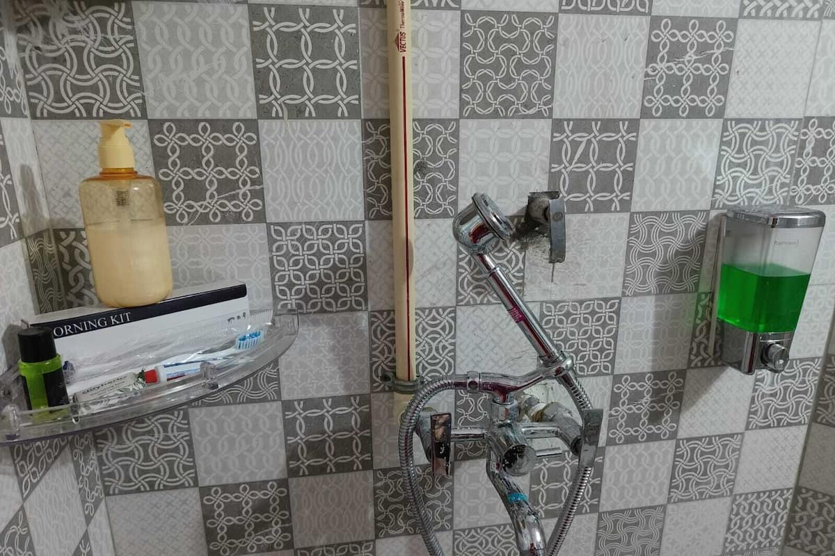 Casa de banho com chuveiro, dispensador de sabão e suporte para escova de dentes.