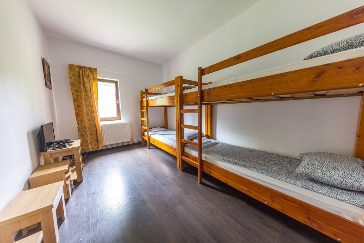 Quarto com beliche, escrivaninha e janela.